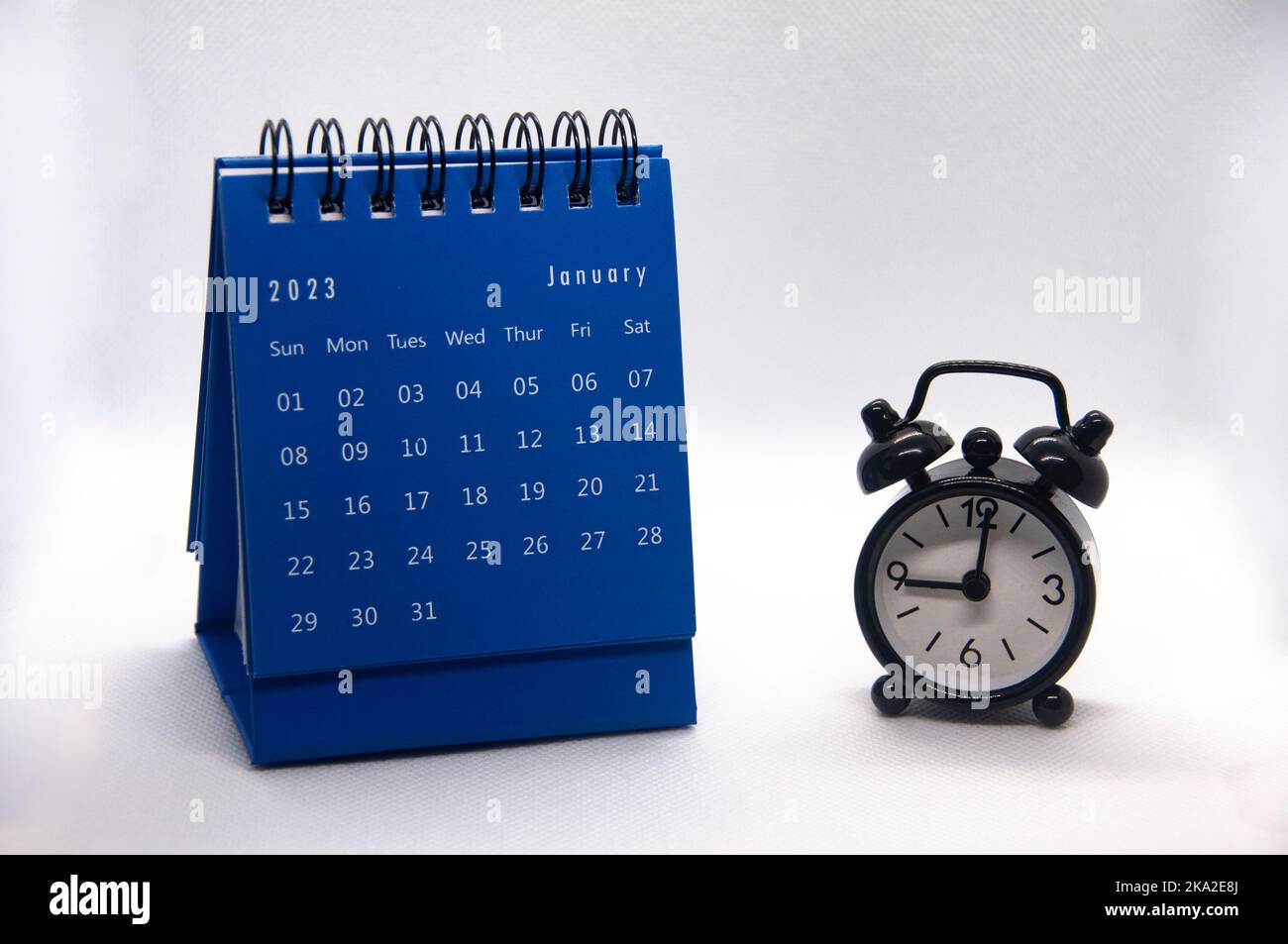 Alarm clock pointing at 9 o'clock with January 2023 calendar on white ... Alarm clock pointing at 9 o'clock with January 2023 calendar on white ...