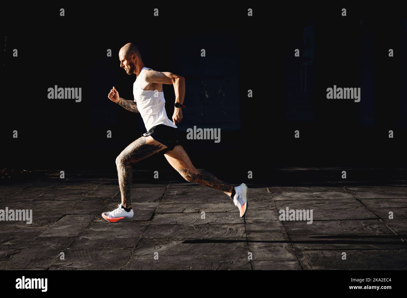 Bald young athletic tattooed man running fast outdoor, sportsman ...