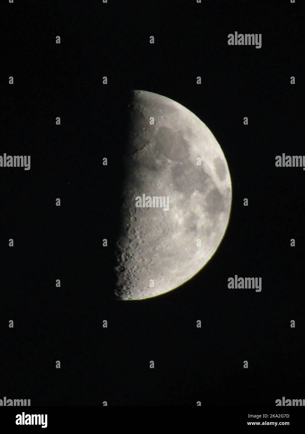 A vertical closeup of a half moon against a black background Stock ...
