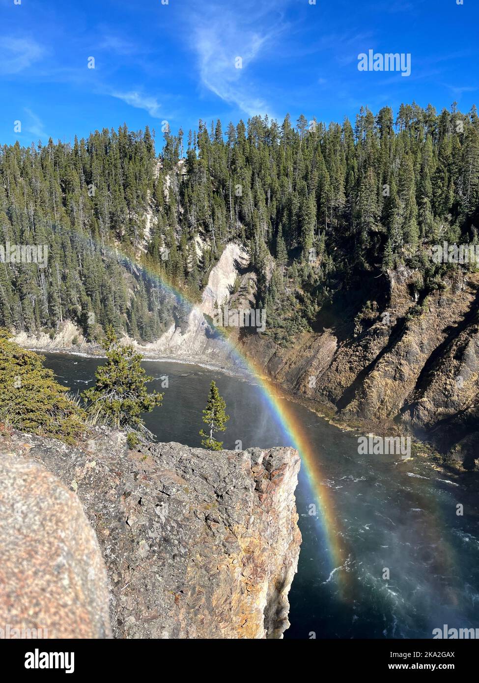 A vertical shot of a rainbow over a river in the Grand Canyon of ...