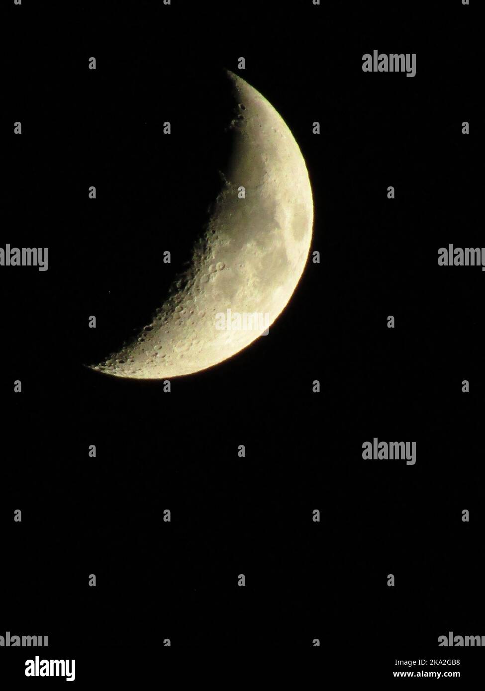 A vertical closeup of a half moon, quarter moon against a black ...