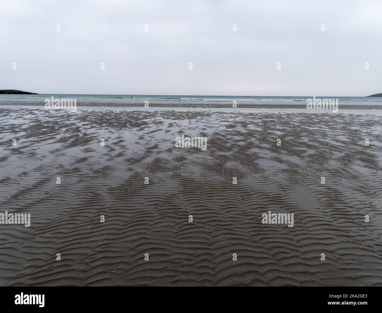 Wet wavy sand on the seashore at low tide on a cloudy day. Gloomy ...