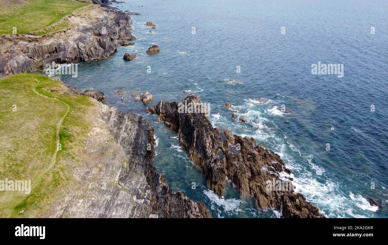 Picturesque rocky coast of the Celtic Sea. White foam on the waves ...