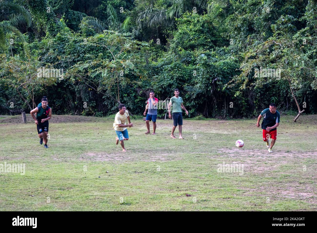 Men from a village in the Amazon region playing football on a grass ...