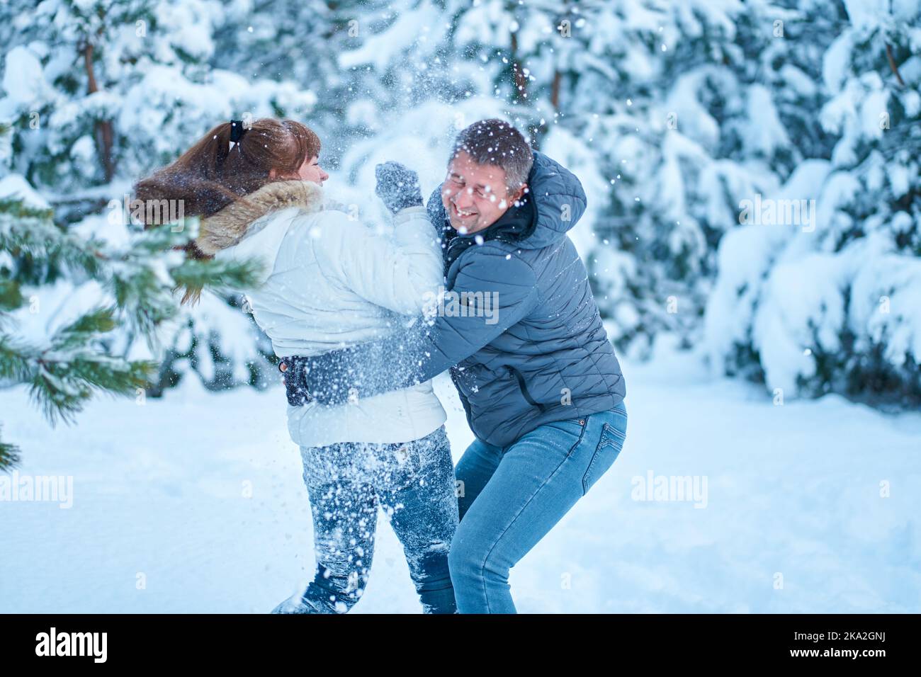 A young couple in love fooling around in the winter woods playing and ...