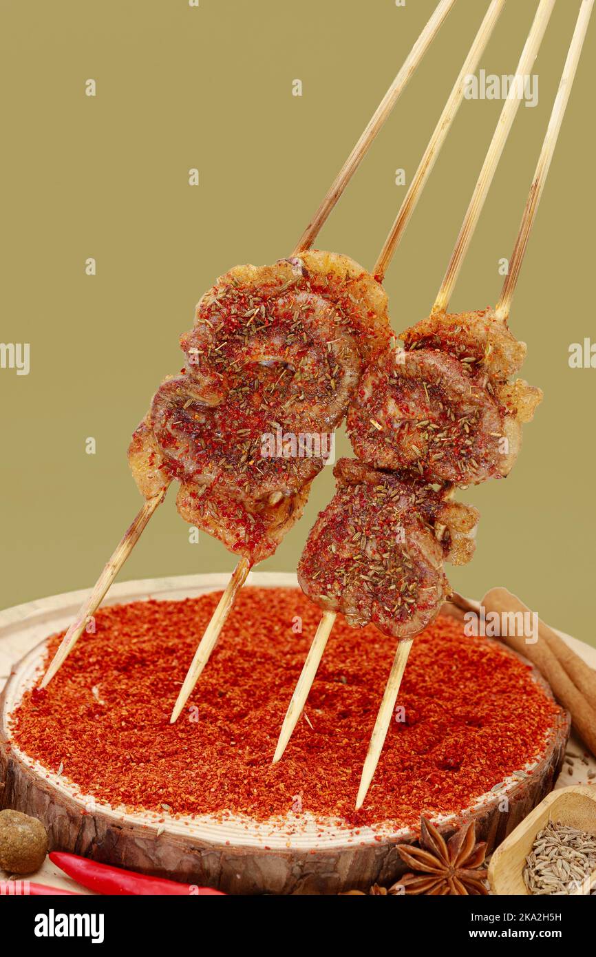 A vertical shot of Sichuan-Style Shao Kao meat on sticks seasoned with ...