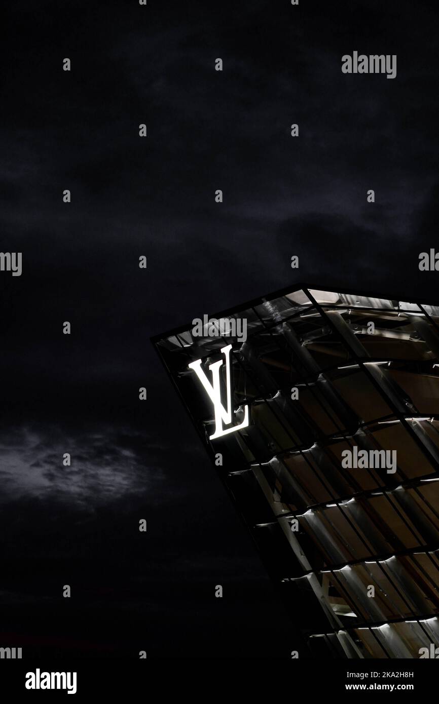 A vertical shot of a Louis Vuitton banner on a building at night in ...