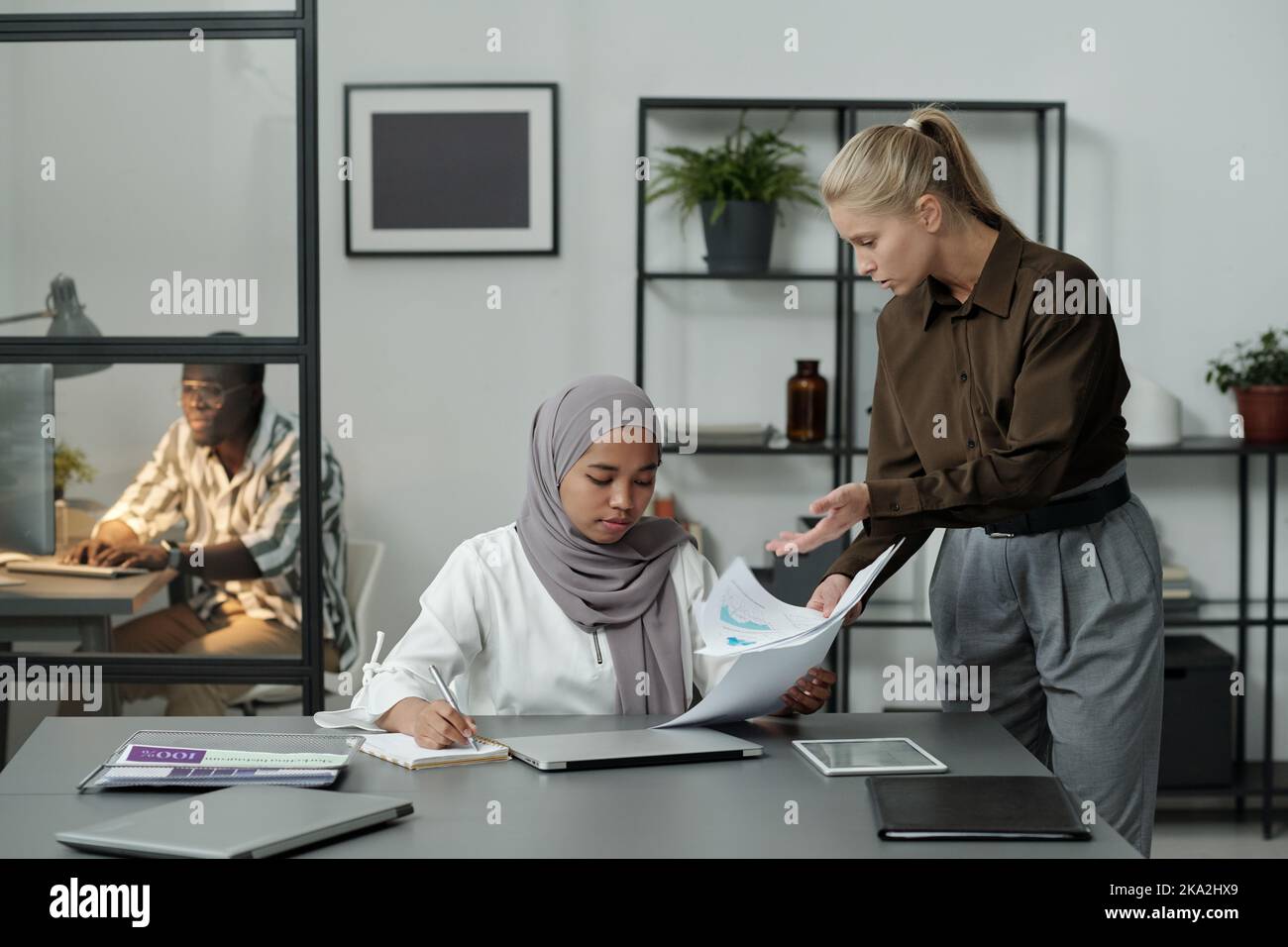 Young blond angry female boss scolding her subordinate in hijab while ...