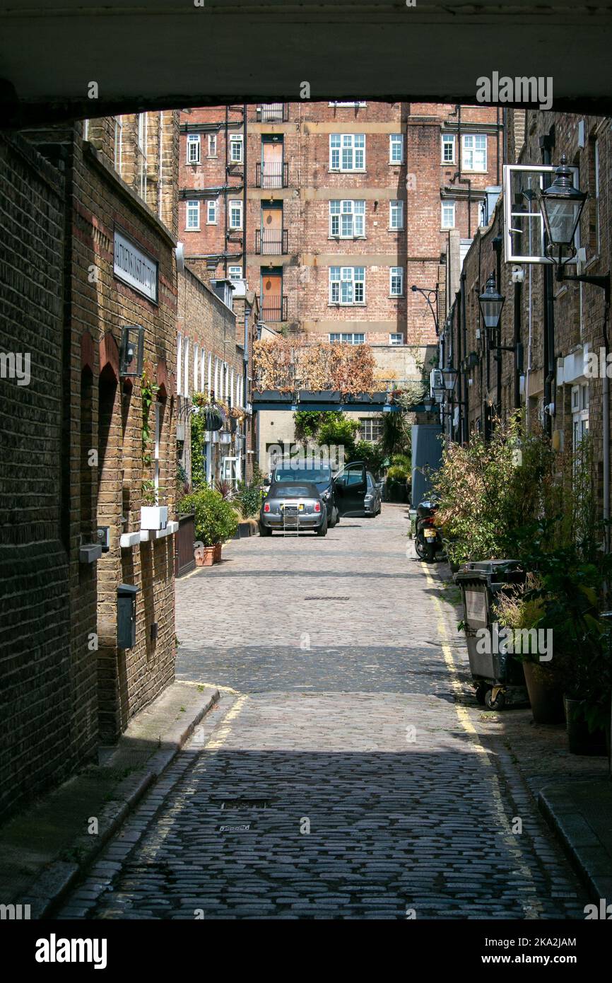 The narrow alleyway in London with cars parked on a sunny day, vertical ...