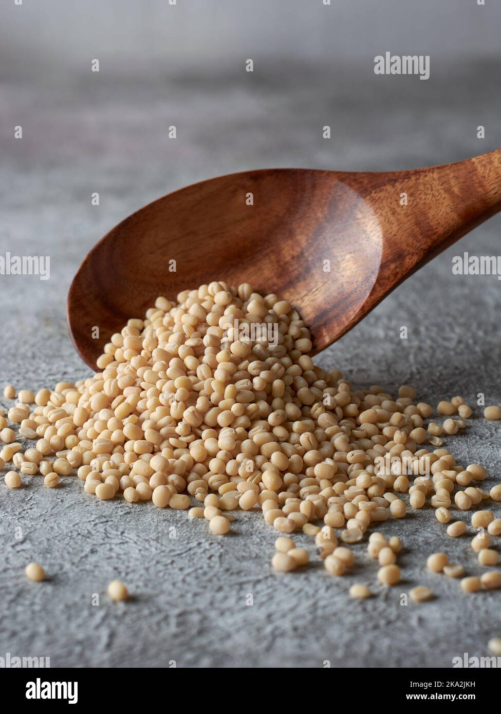 pile of organic polished white urad dal fallen from a wooden spoon ...