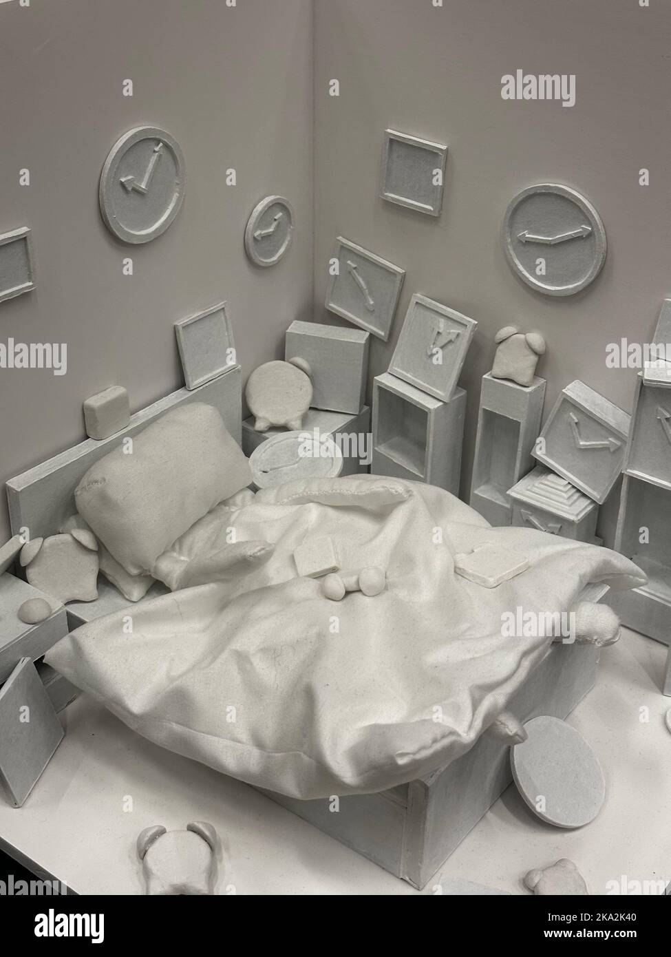 The vertical high-angle view of a bed with clocks all over - grayscale ...