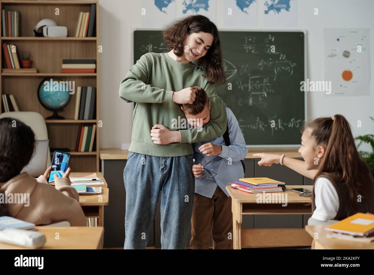 Two girls laughing at junior school learner while one of them making ...