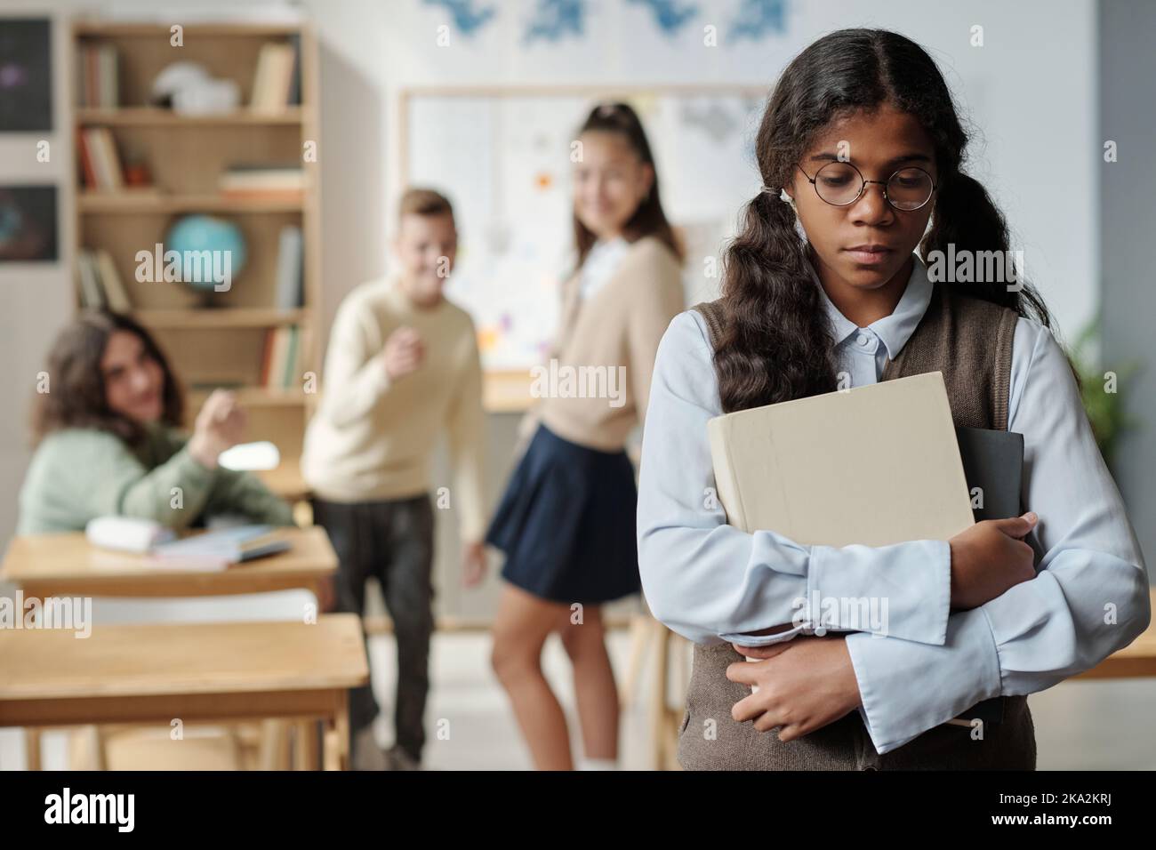 Pre-teen upset schoolgirl with books standing in front of camera with ...