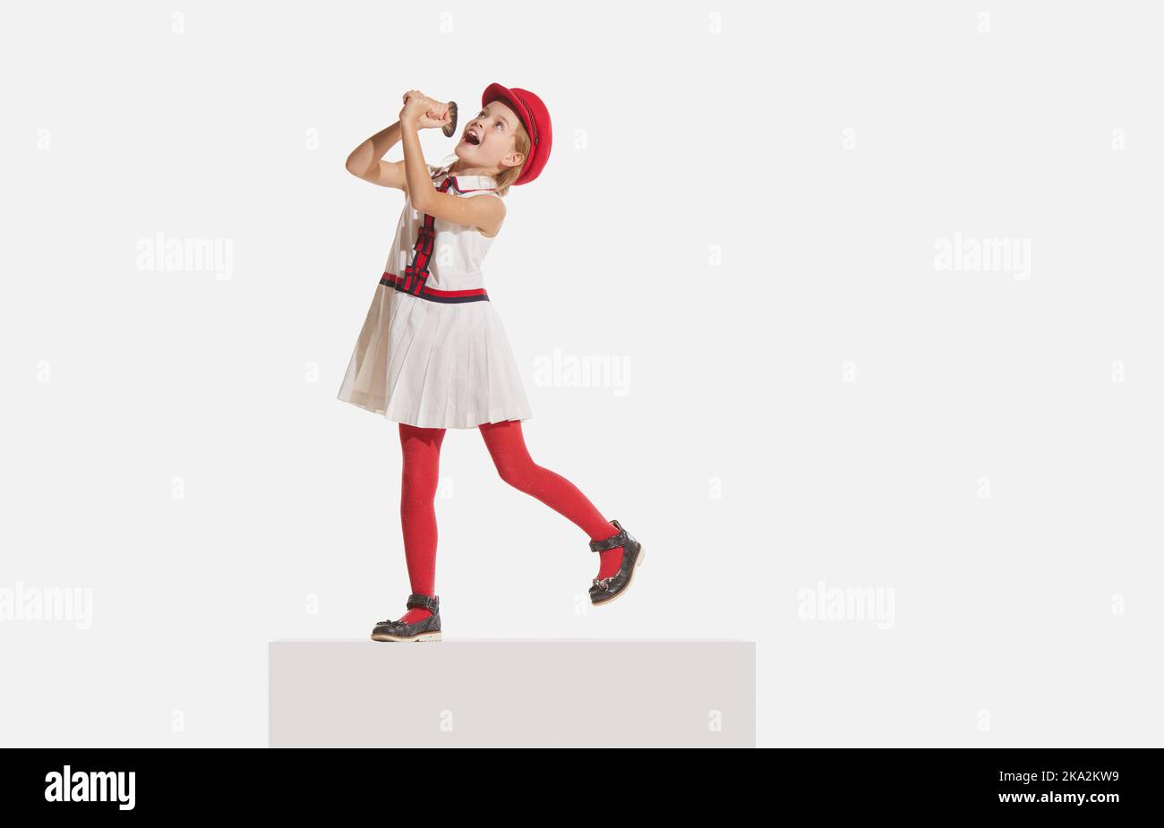 Happy little cute stylish girl, kid in retro fashion outfit singing ...