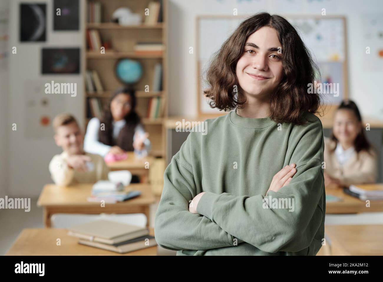 Smiling pre-teen secondary school learner in grey sweatshirt crossing ...