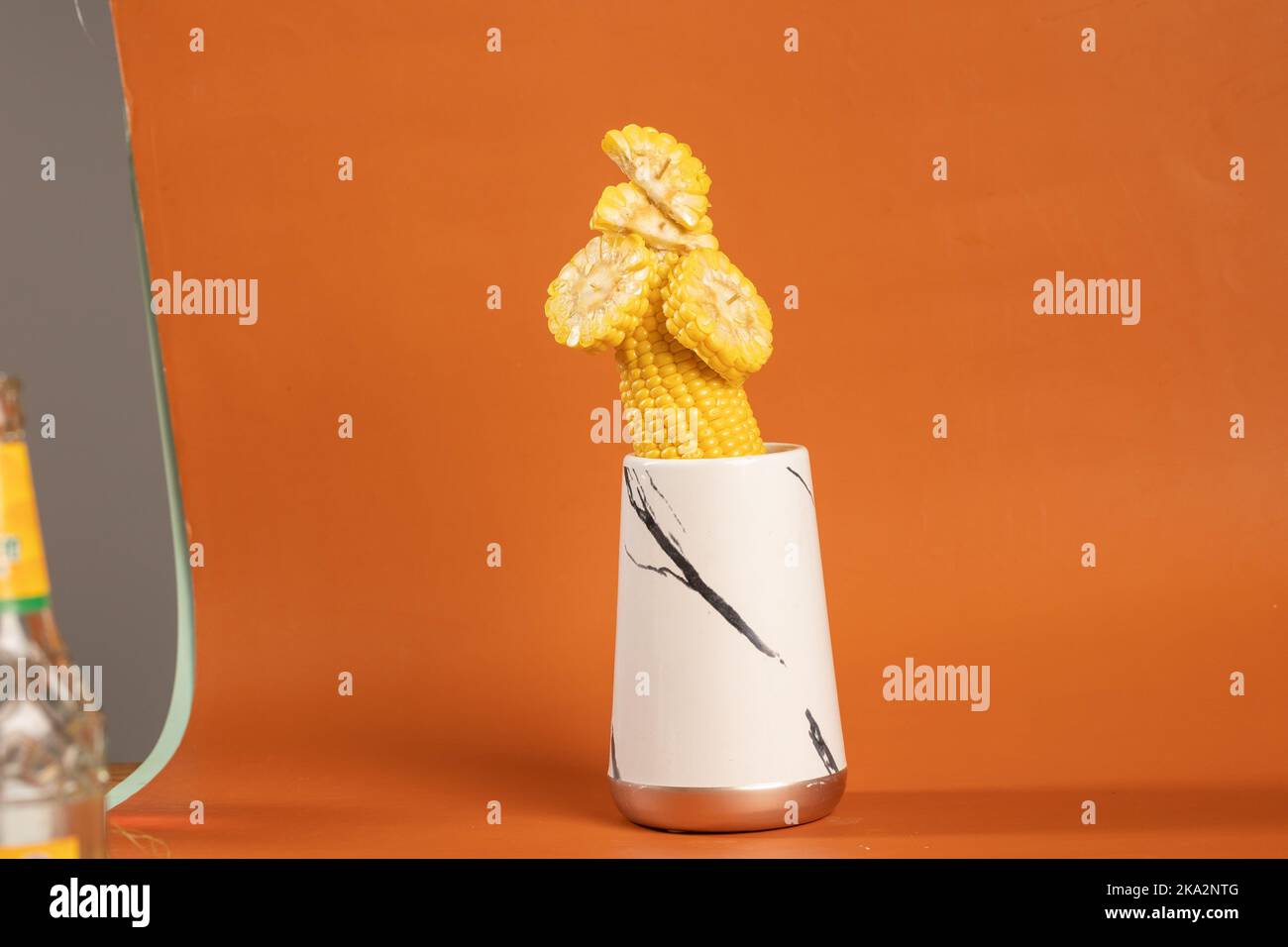 A marble vase with a corn on the cob and sliced corn pieces on an ...