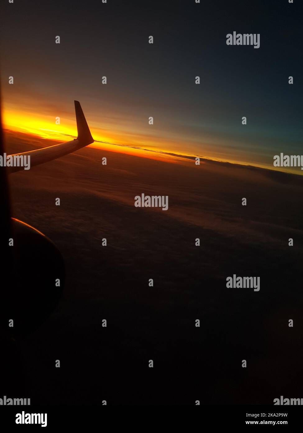 A vertical shot of a view of a sunset through an airplane window with ...
