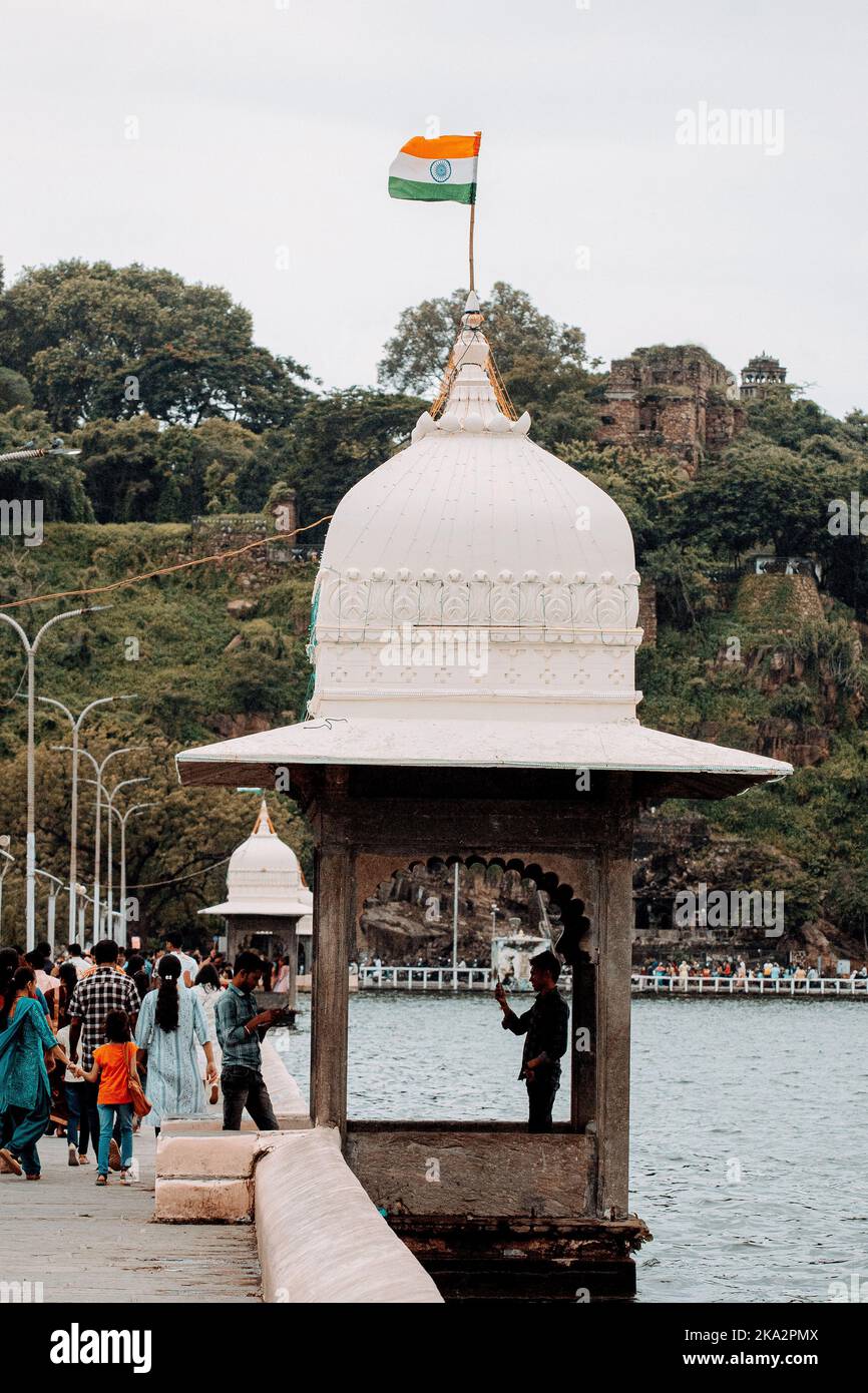 A temple with the Indian flag in Udaipur city with Fateh Sagar lake in ...