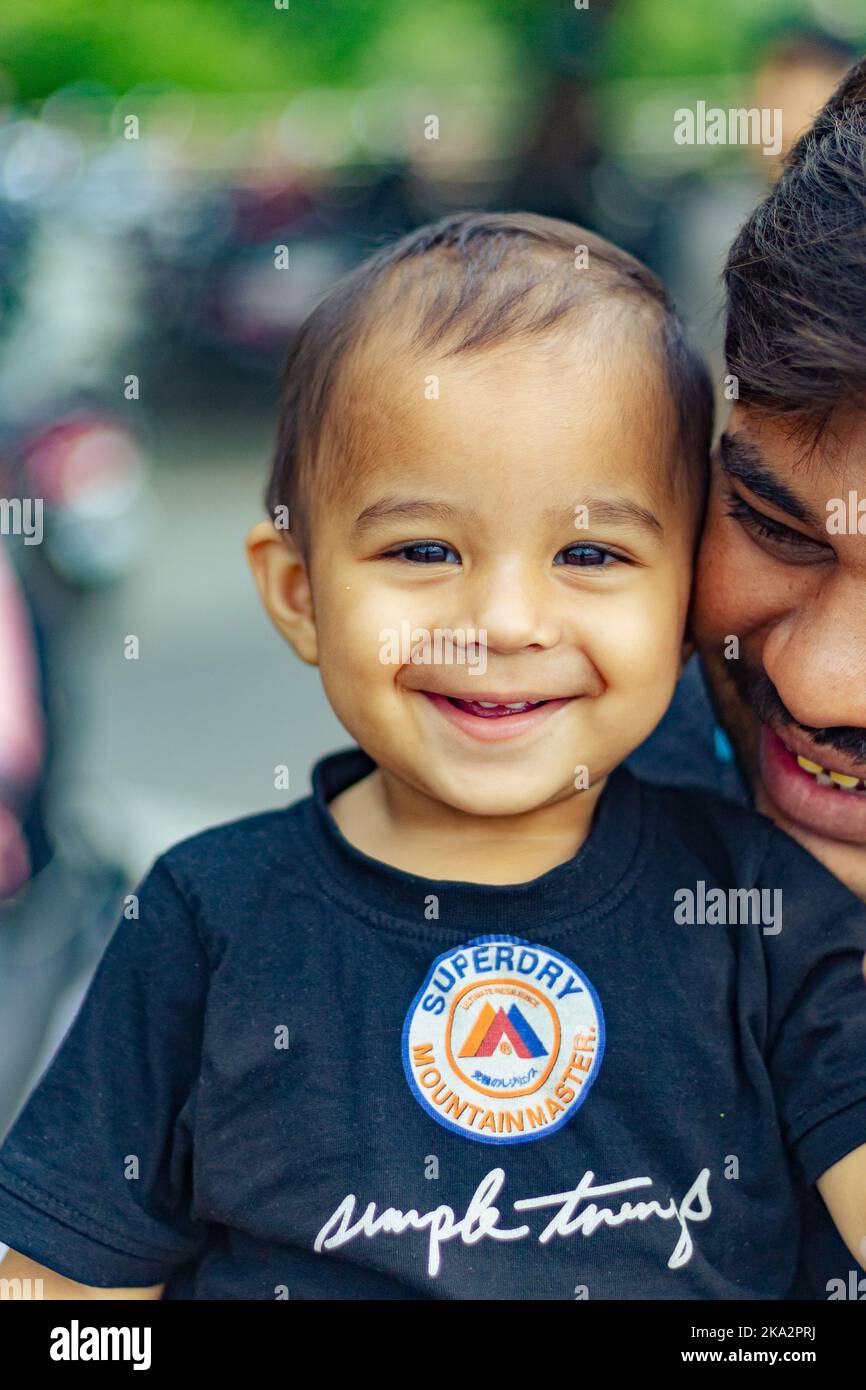 A vertical closeup of a baby smilng in person's arms in Udaipur India ...