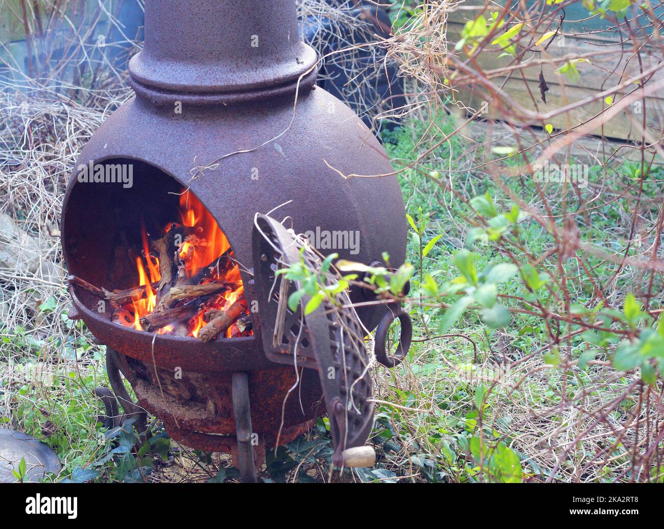 Fire blazing in a garden chimenea. Yellow and red flames. warming and ...