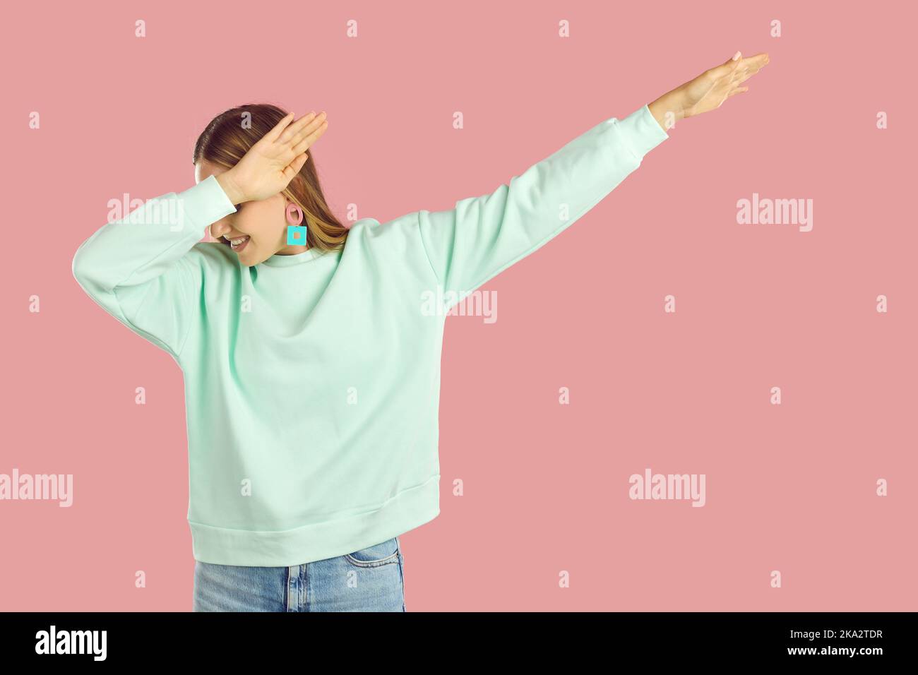 Cheerful woman covers her face with one arm and takes other aside ...