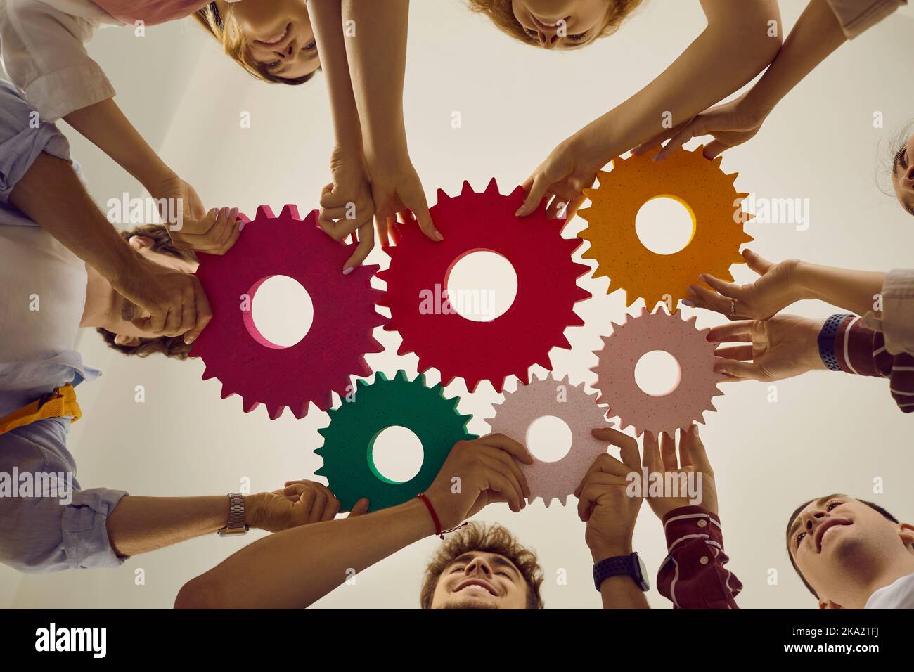 Colorful gears in hands of positive college students standing in circle ...