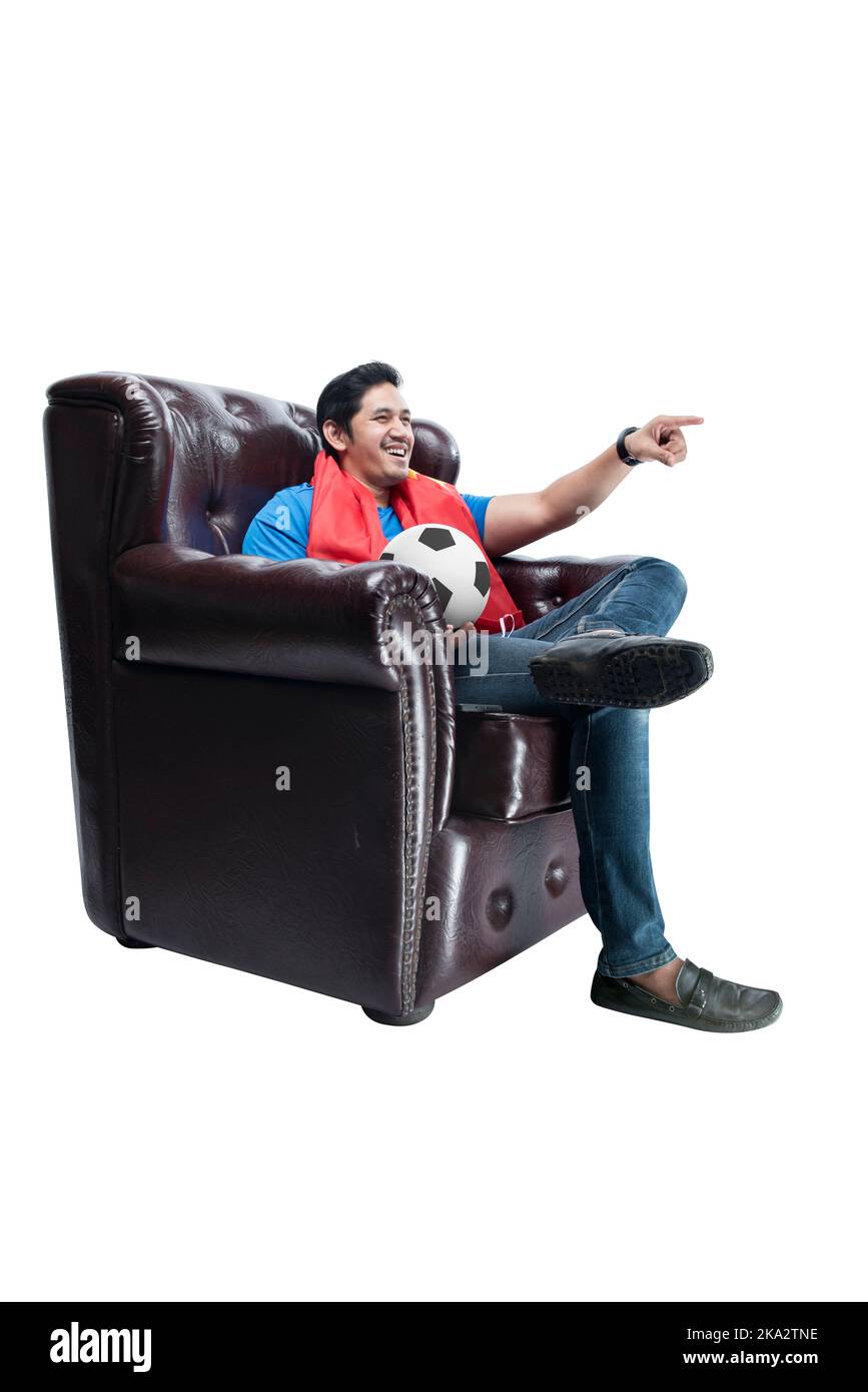 Asian man with scarf and ball sitting on the couch isolated over white ...