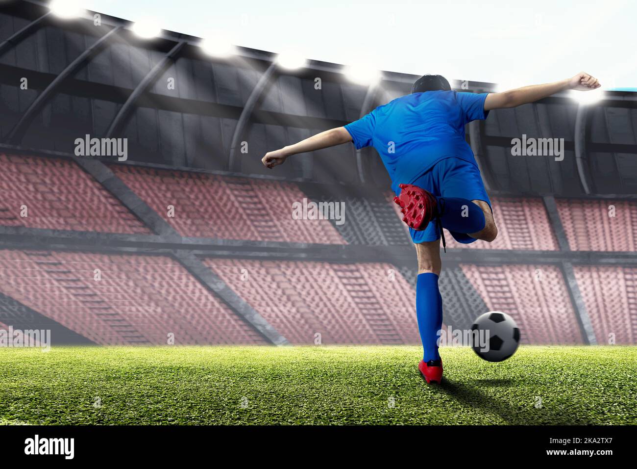 Rear view of a football player man in a blue jersey kicking the ball on ...