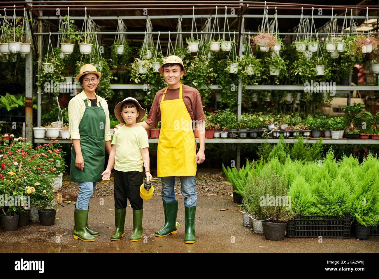 Happy parents and son in rubber boots and aprons standing in their ...