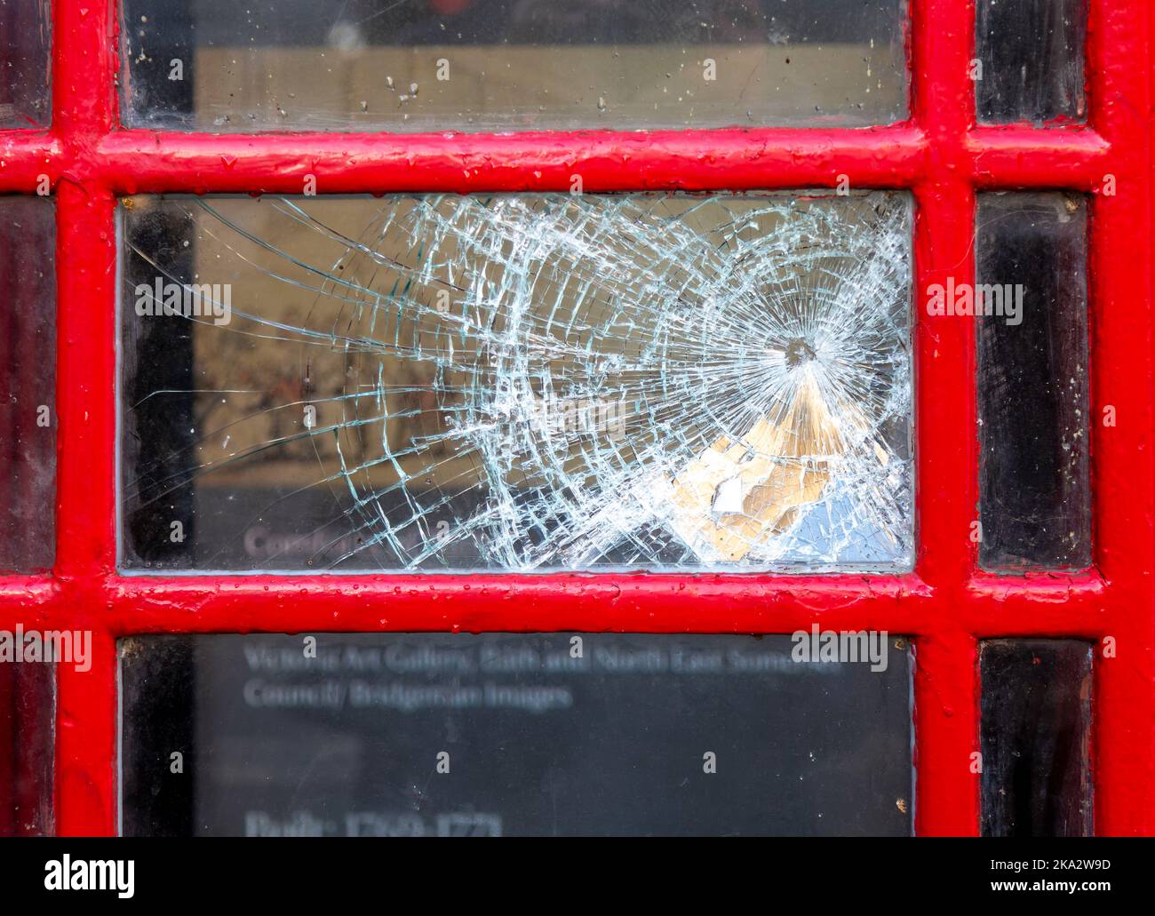 Smashed vandalised glass panel of old red telephone box, Bath, Somerset ...