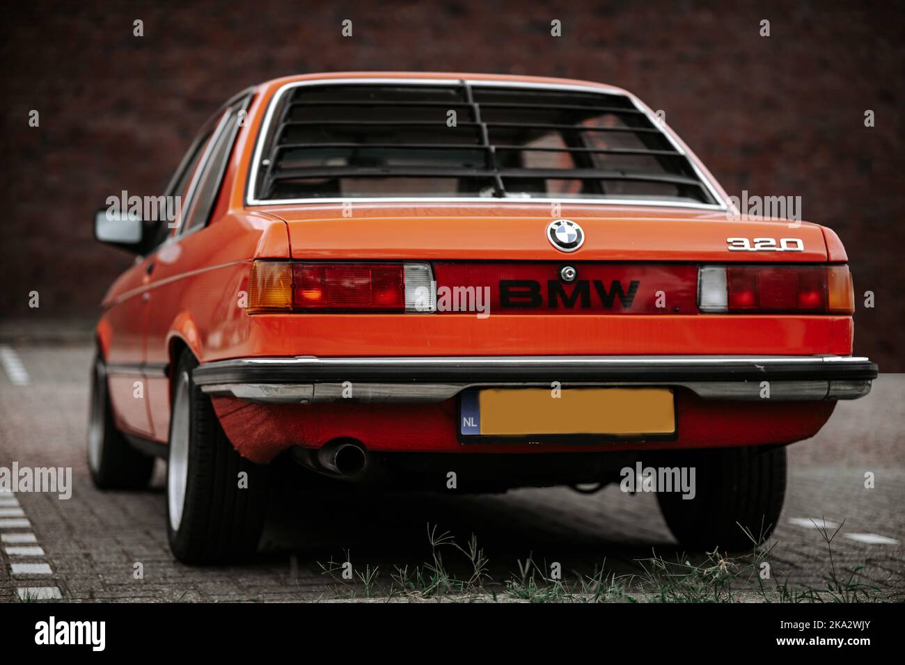 A close-up shot of the back of an orange classic retro BMW 320 car at a ...