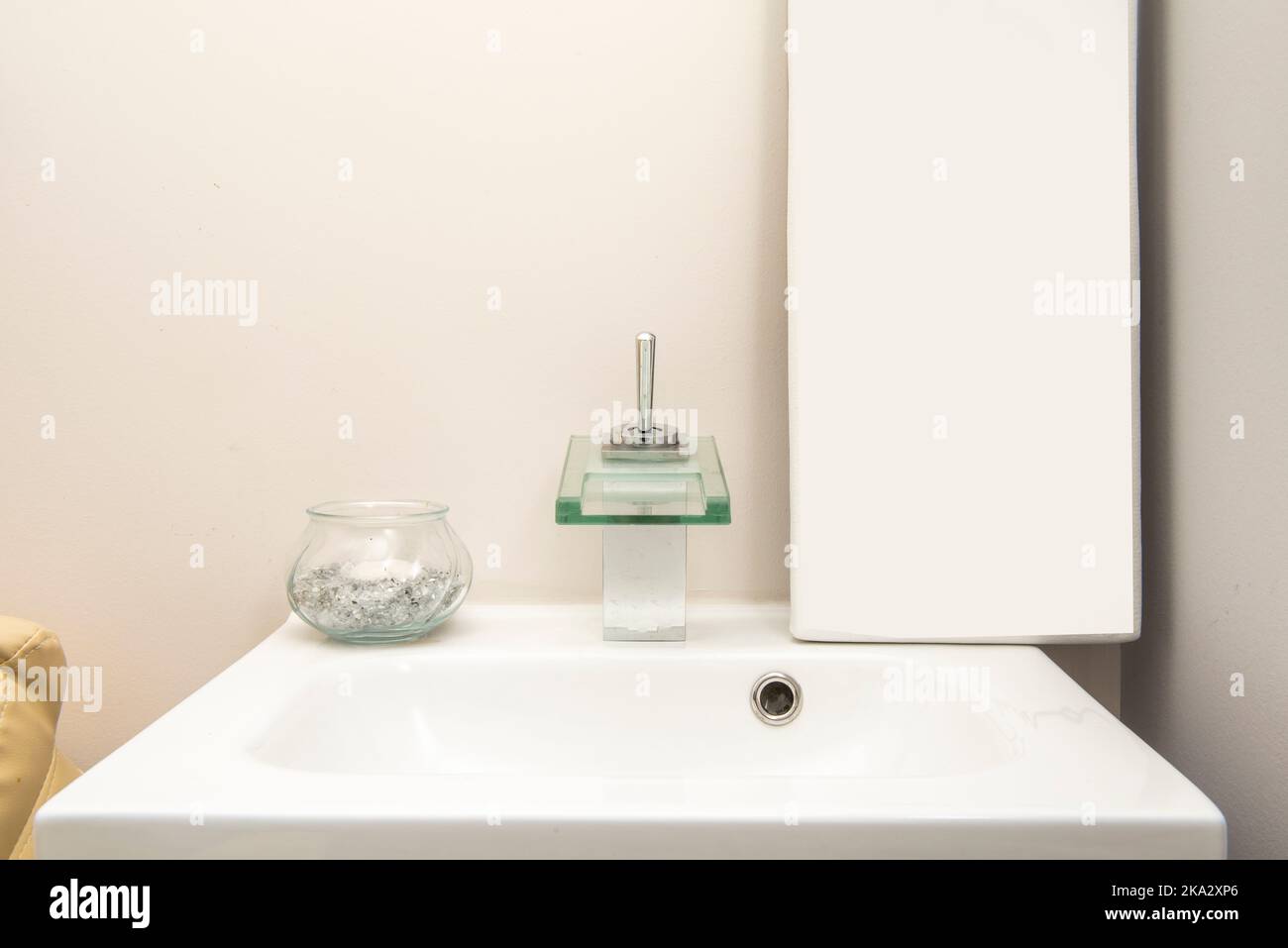 white porcelain sink with designer faucet and candle in glass container ...