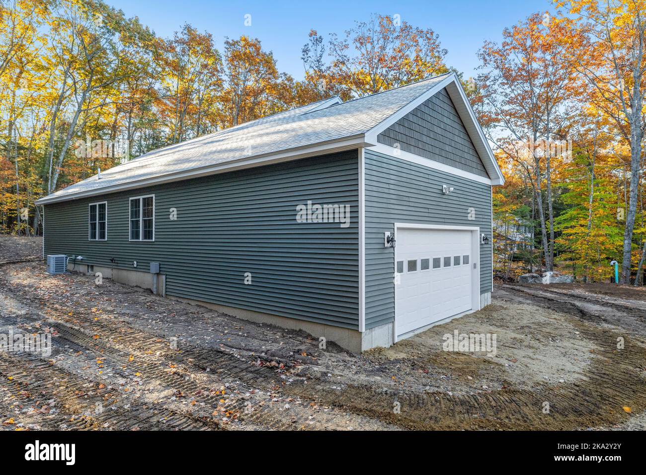 A house with grey exterior and an automatic garage built in a forest ...