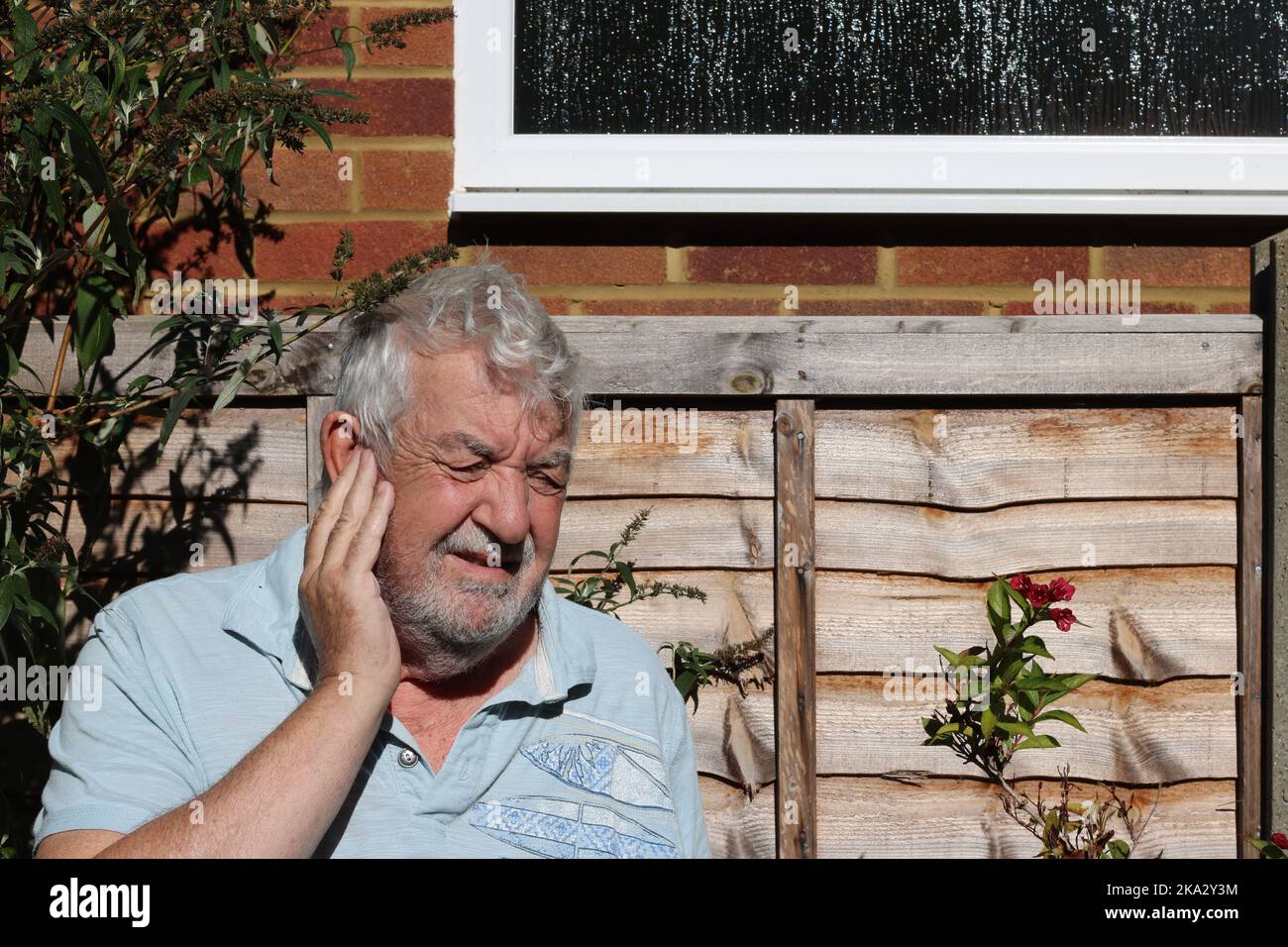 Elderly man with earache. In great pain and holding his ear. Ear ...