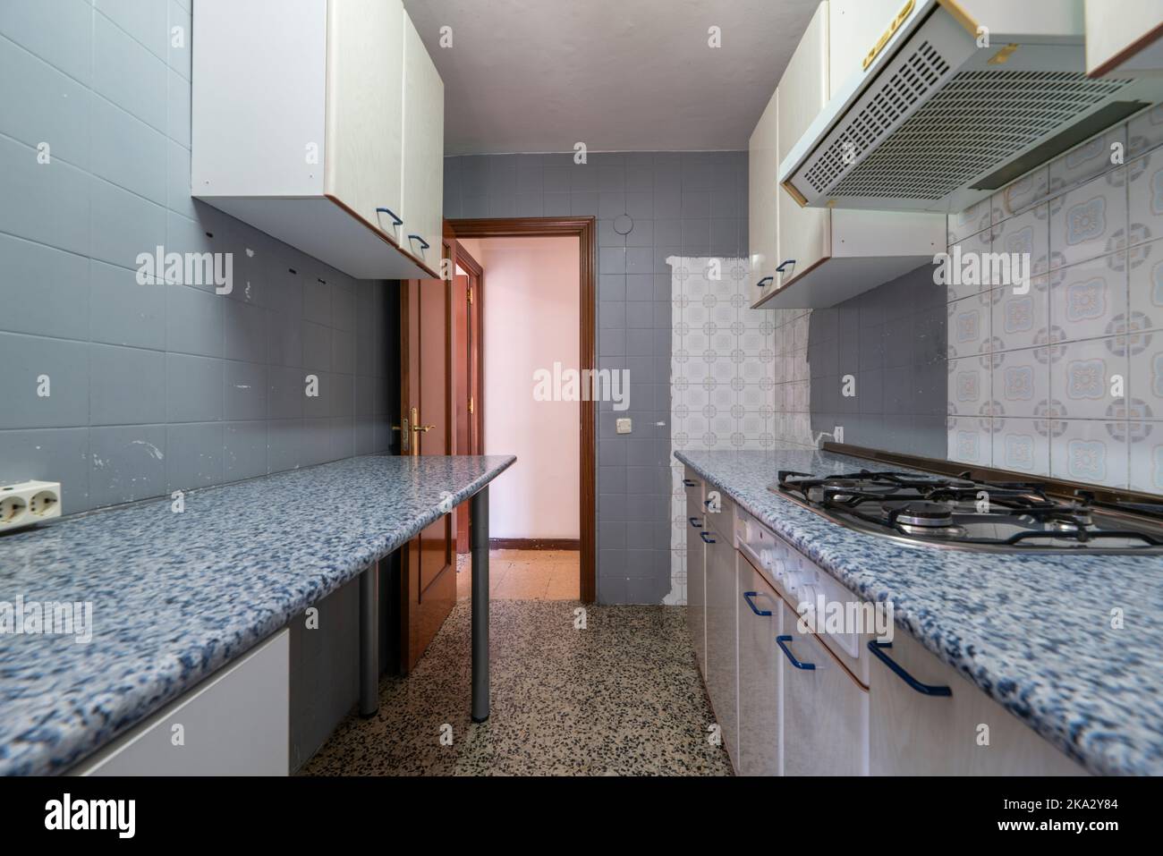 Old kitchen with blue countertops on both sides and dirty terrazzo ...