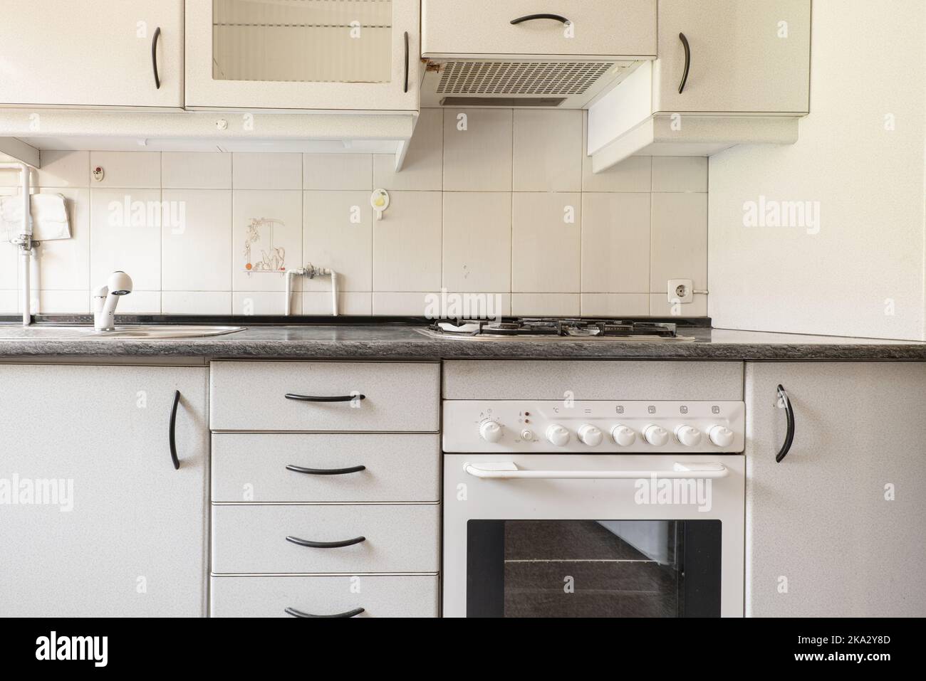 Front view of a vintage white kitchen with gray countertops and ...