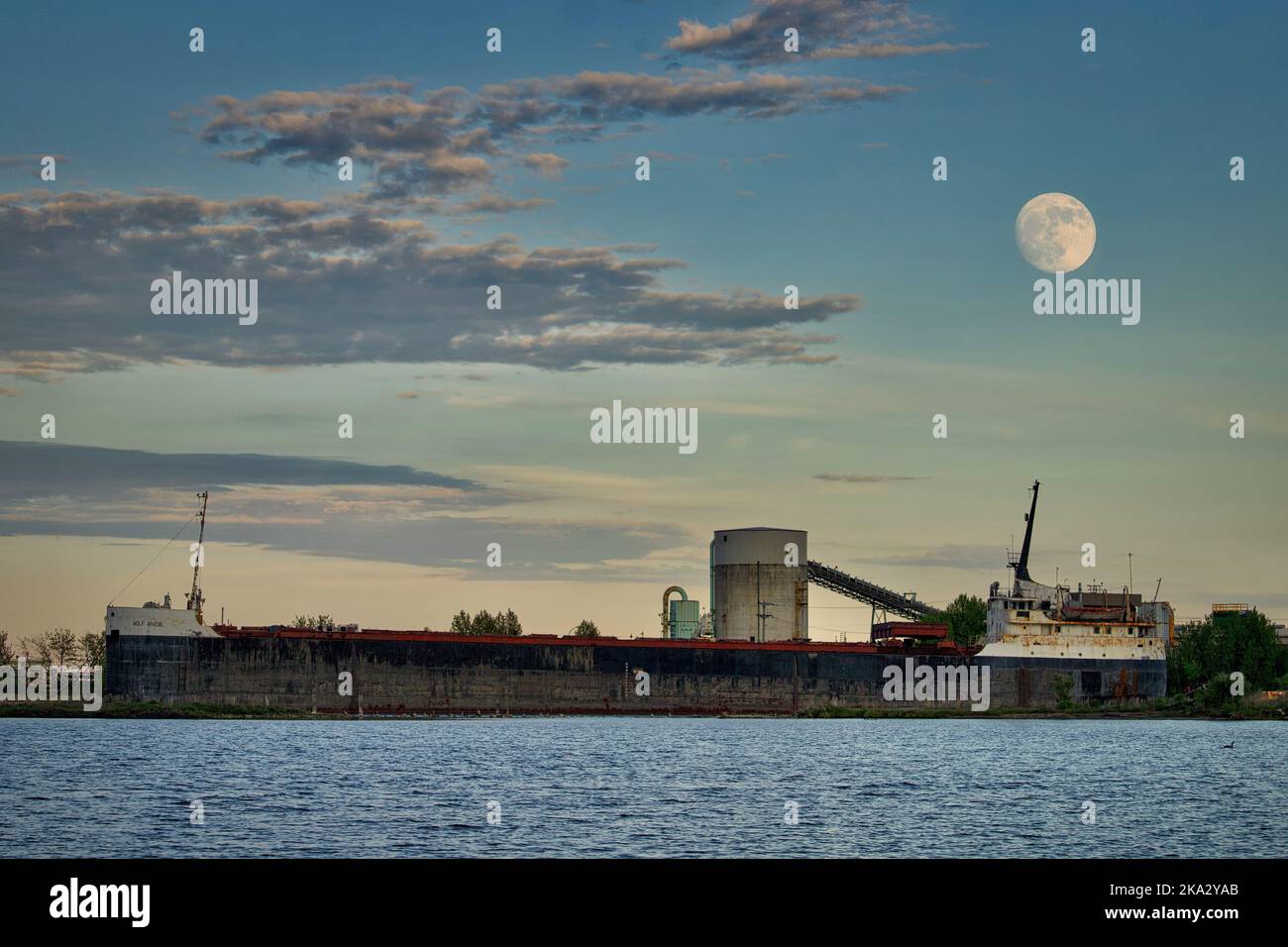 A scenic sunset view of a port and a full moon Stock Photo - Alamy