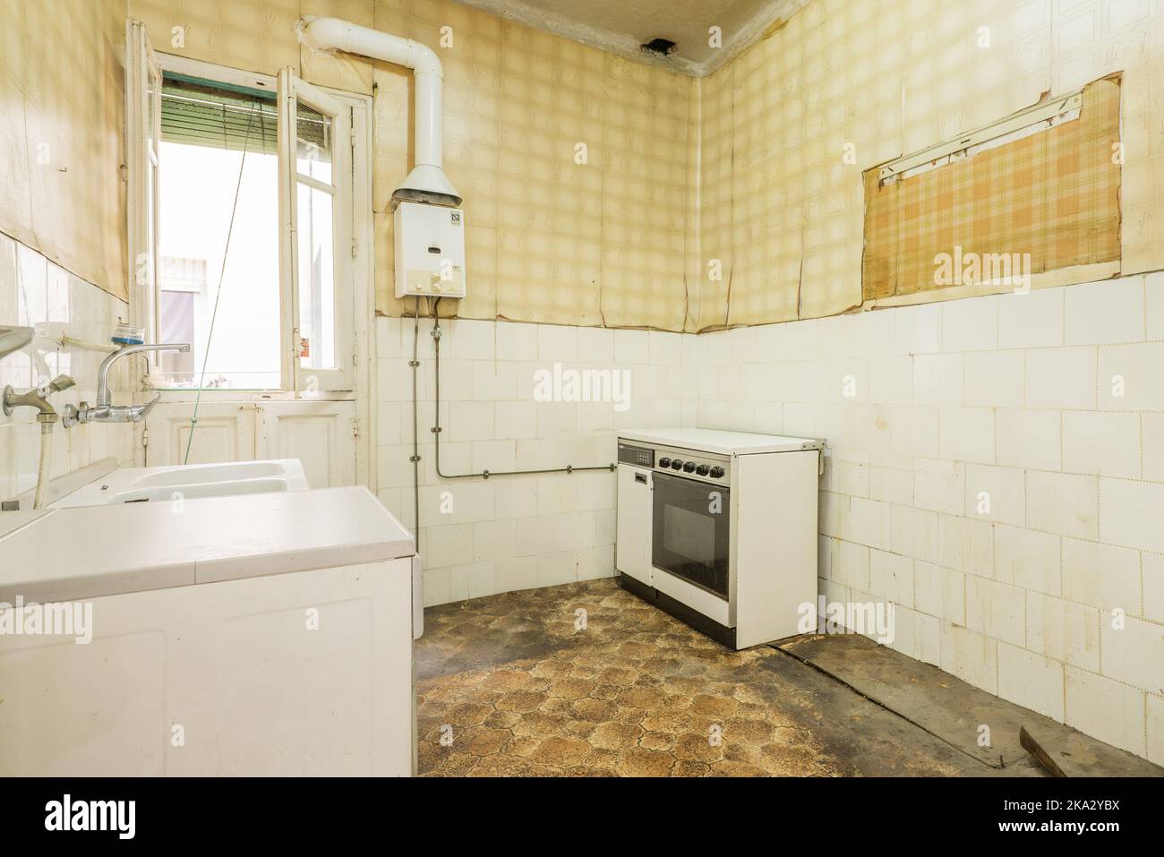 Dilapidated dirty old kitchen with dark floor, white tiles and yellow ...