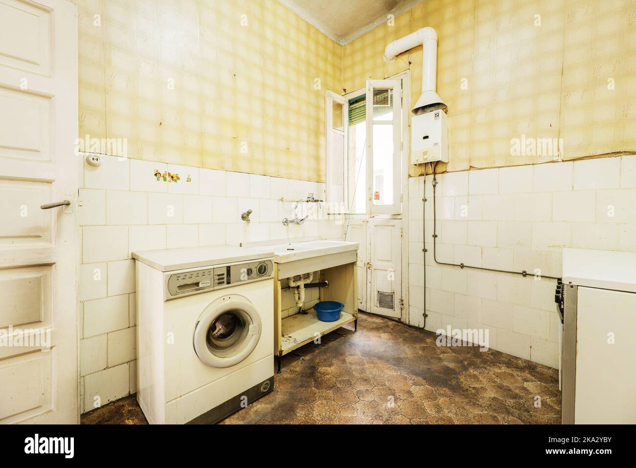 Dilapidated old dirty kitchen with dark floor, white tiles and yellow ...
