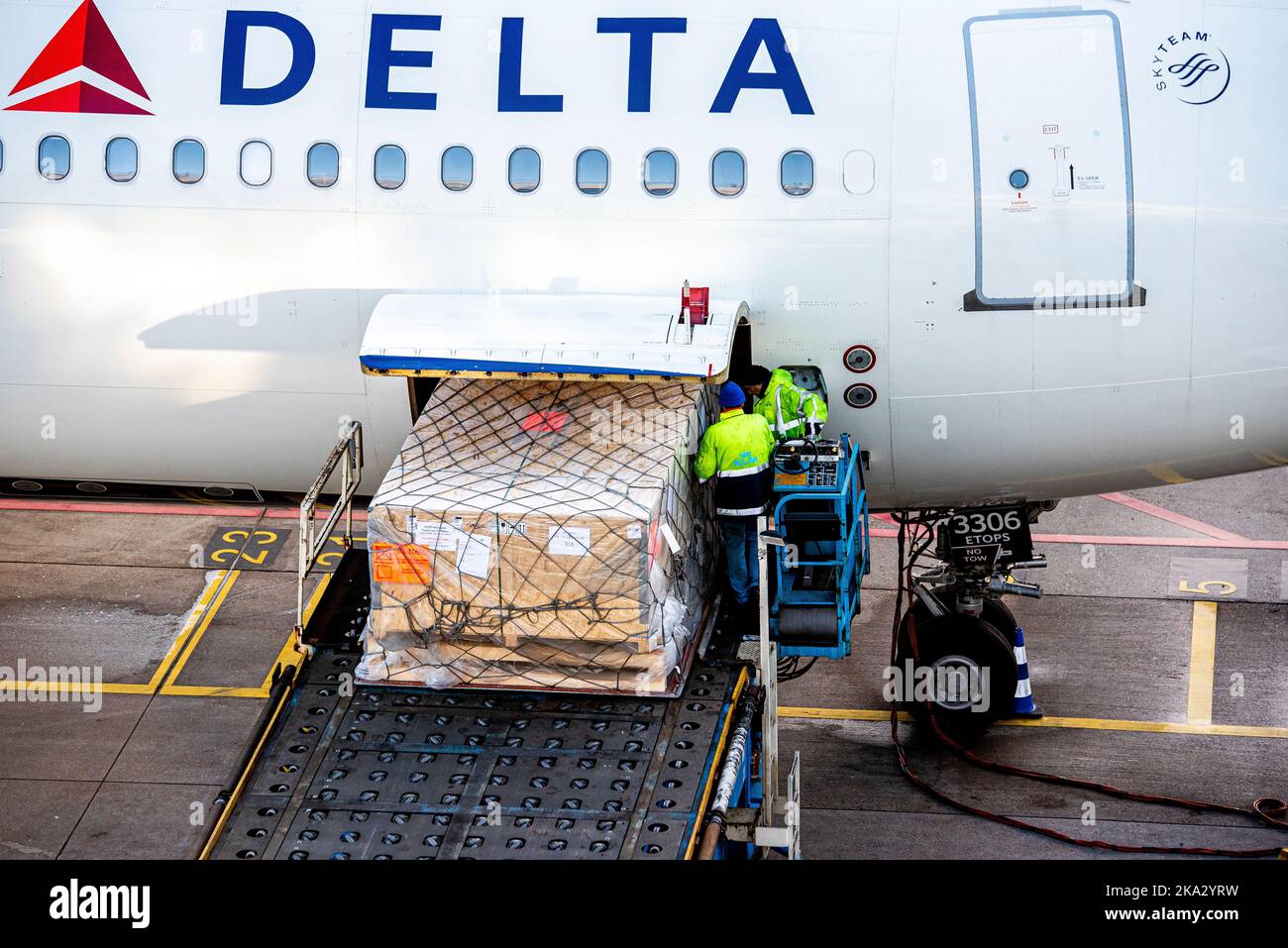 A closeup of people loading cargo into the Delta airplane at Schiphol ...