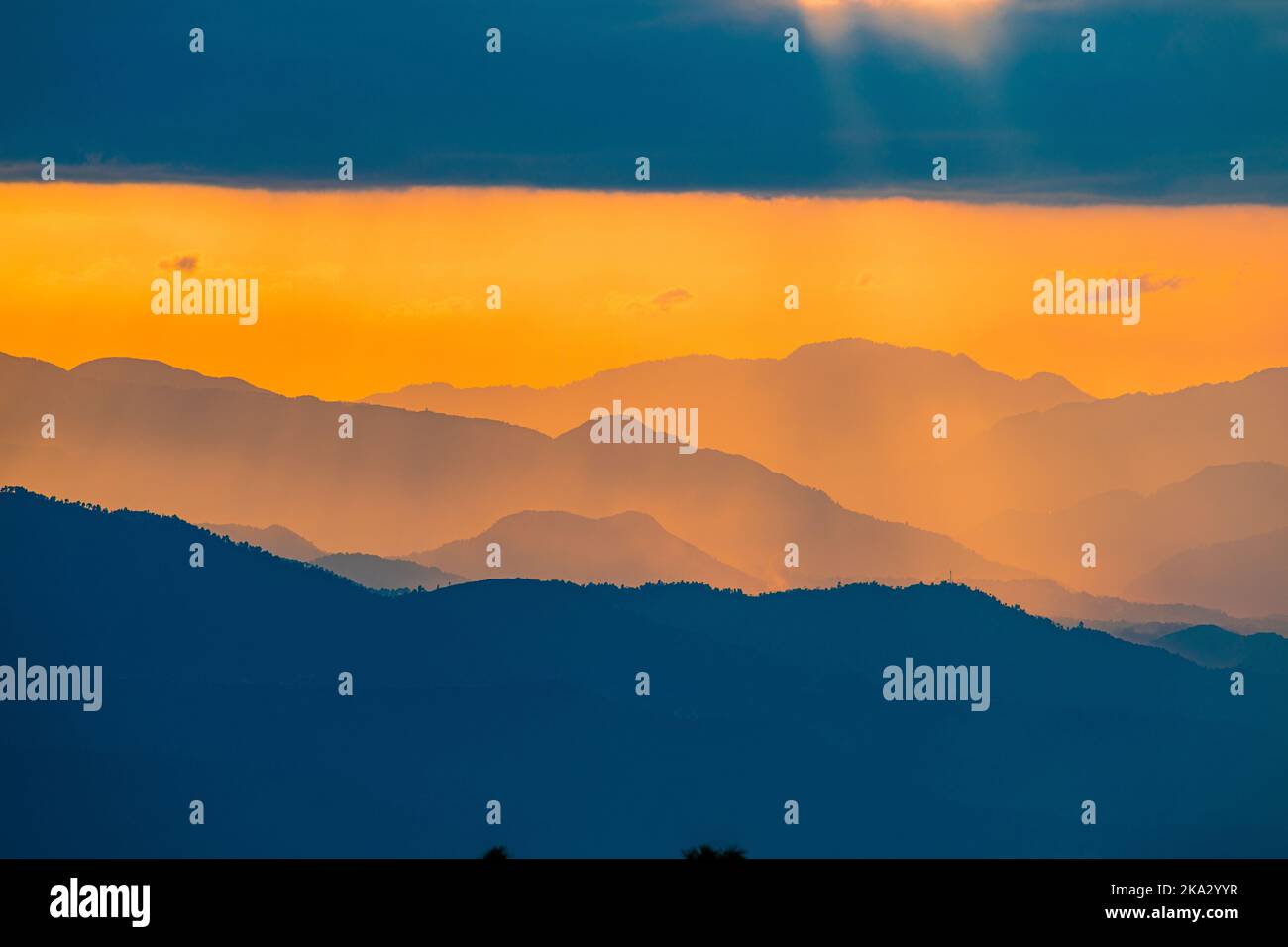 A mesmerizing soft orange sunset over the silhouette of hills Stock ...