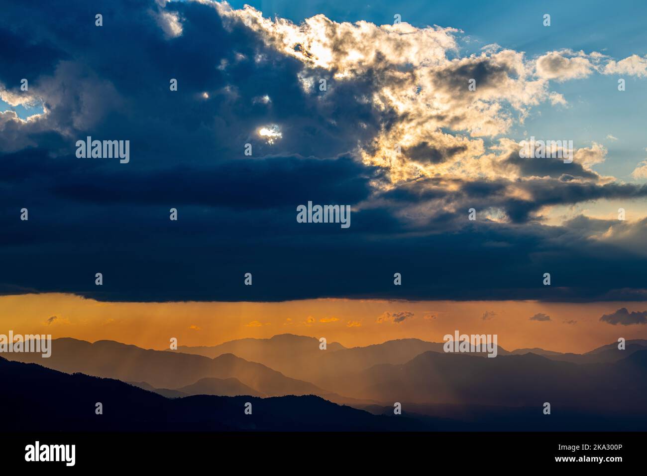 A mesmerizing soft orange sunset over the silhouette of hills with ...
