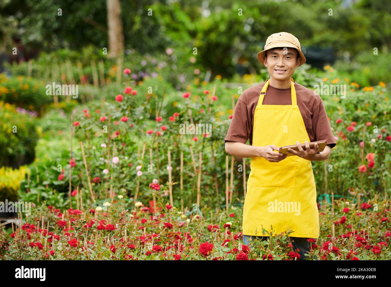 Portrait of plant nursery owner with digital tablet checking quality of ...