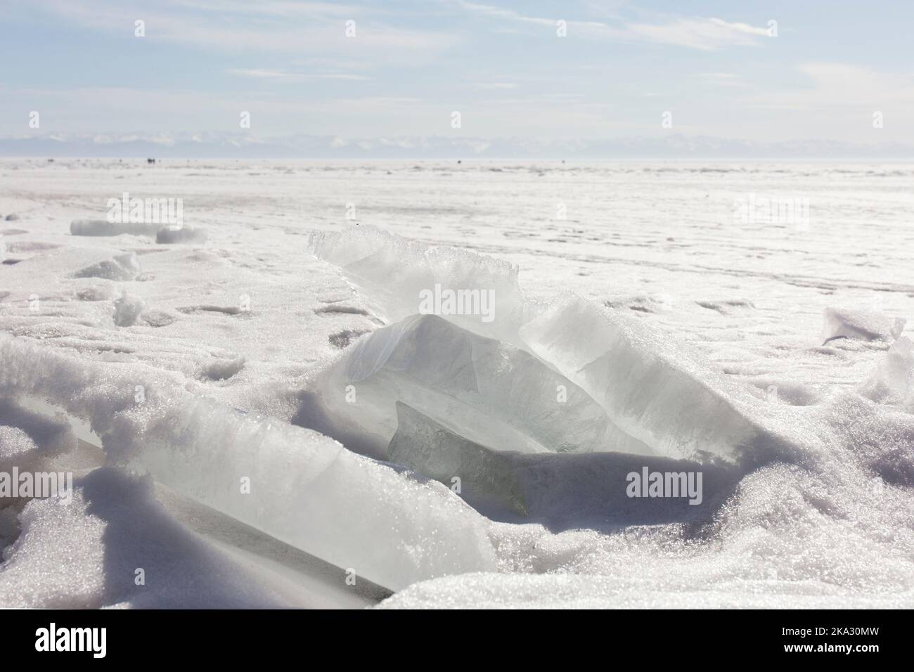 Transparent blue ice hummocks on lake Baikal shore. Siberia winter landscape view. Snow-covered ...