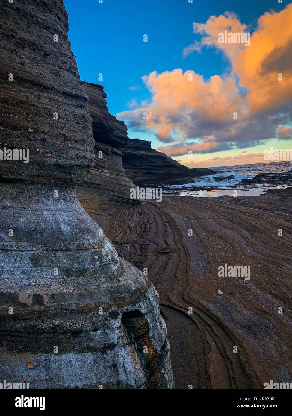 A vertical shot of sedimentary rocks on the coastline of the sea at ...