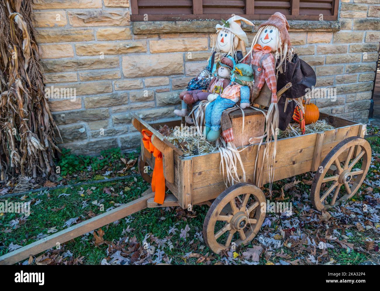 A scarecrow family in a small wooden wagon stuffed with hay and ...