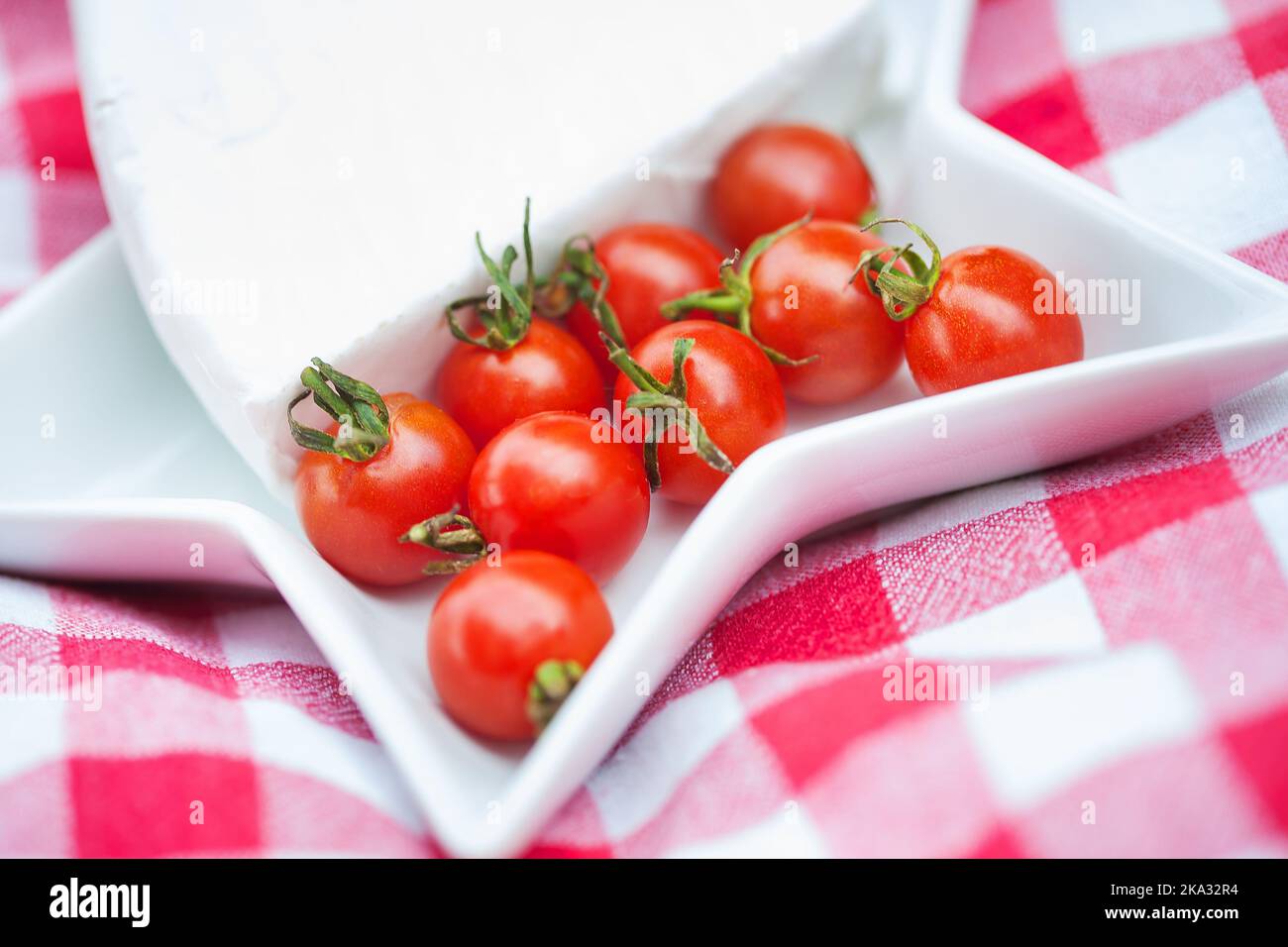 brie cheese and cherry tomatoes on a red tablecloth. close up Stock ...