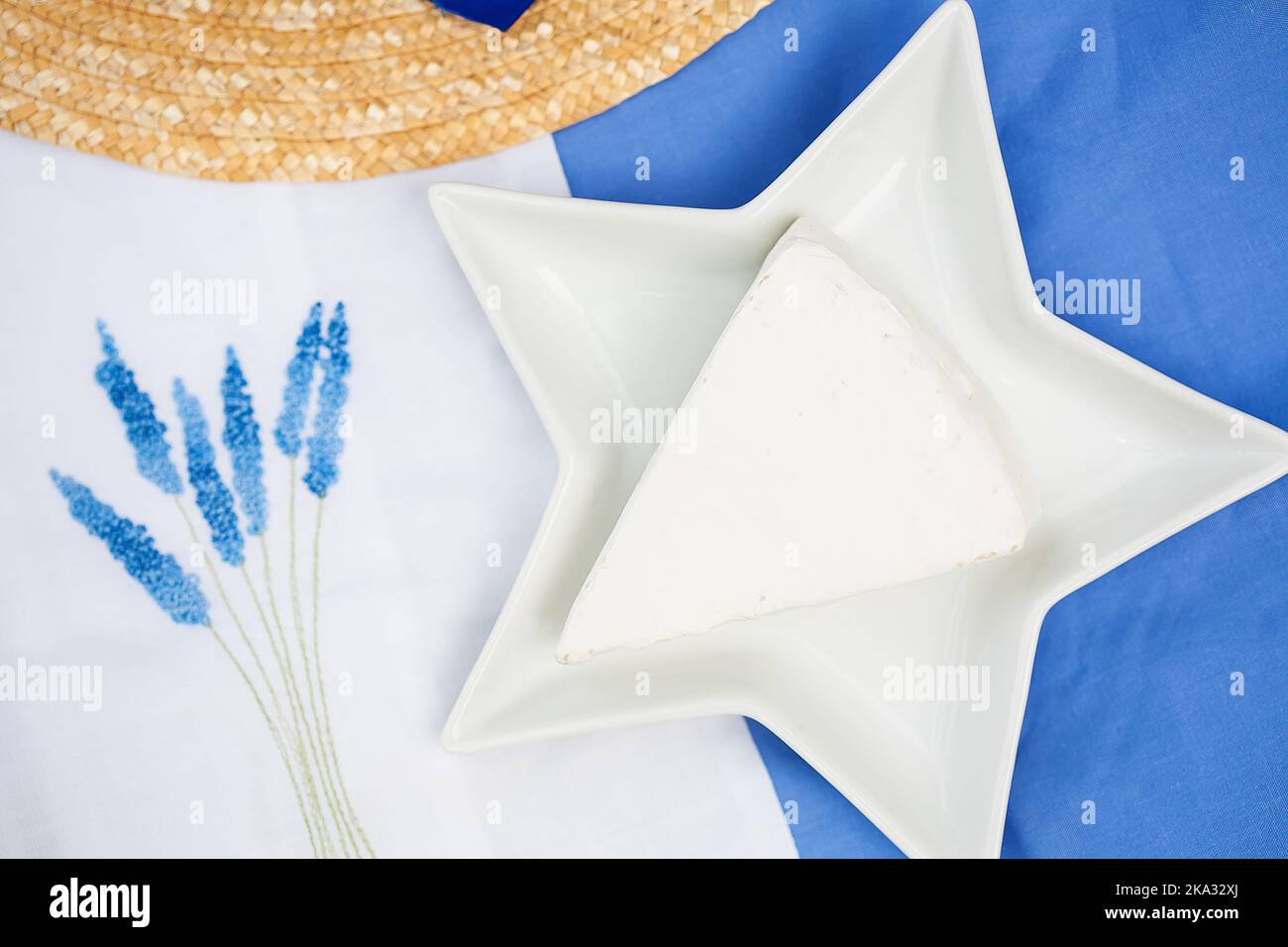 hat, brie cheese in a plate on a blue tablecloth Stock Photo - Alamy
