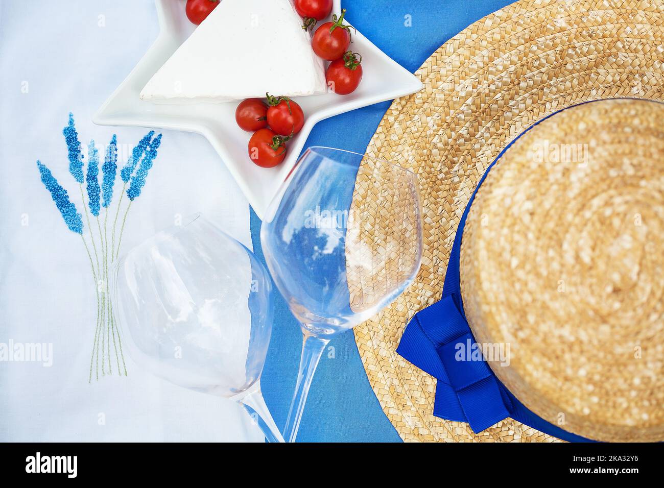 cheese, tomatoes, glasses and hat on blue tablecloth Stock Photo - Alamy