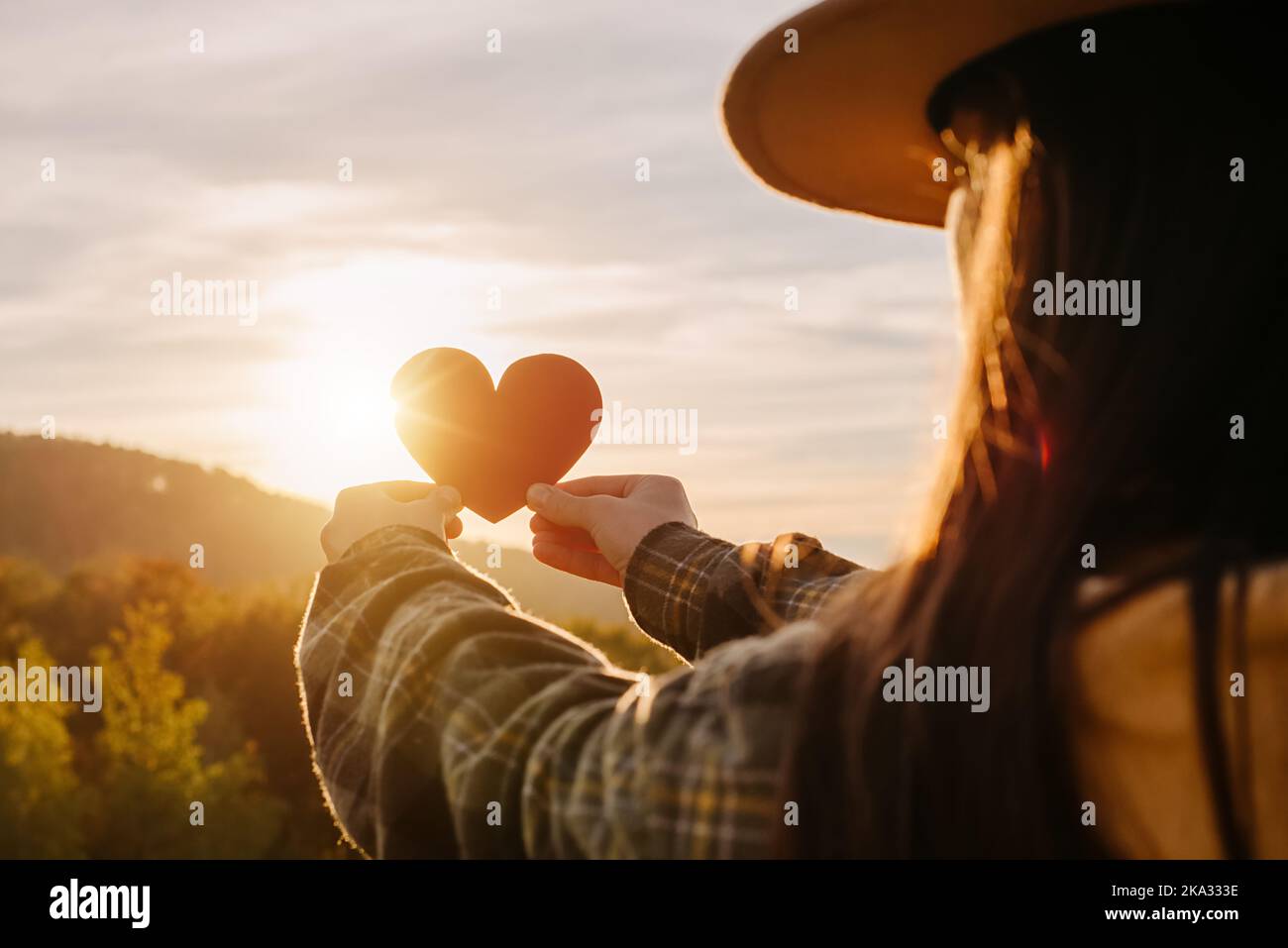 Close up of young woman in hat holding small red heart on background ...